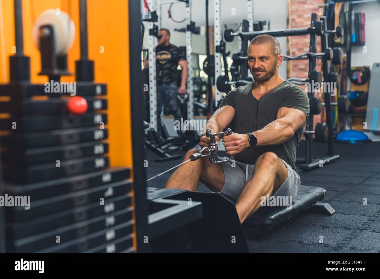 muscular sportsman working out with a rowing machine at the gym, full ...