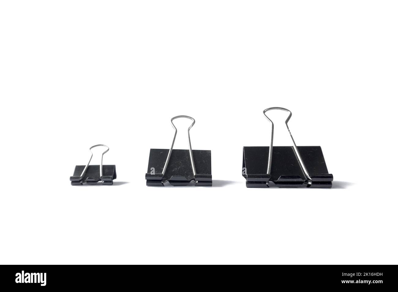 Three black binder clips of various sizes used to staple documents ...