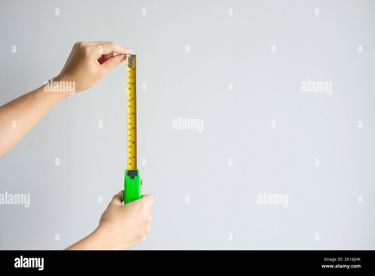 Man hand using tape measure for measuring with wall backgrounds at home ...