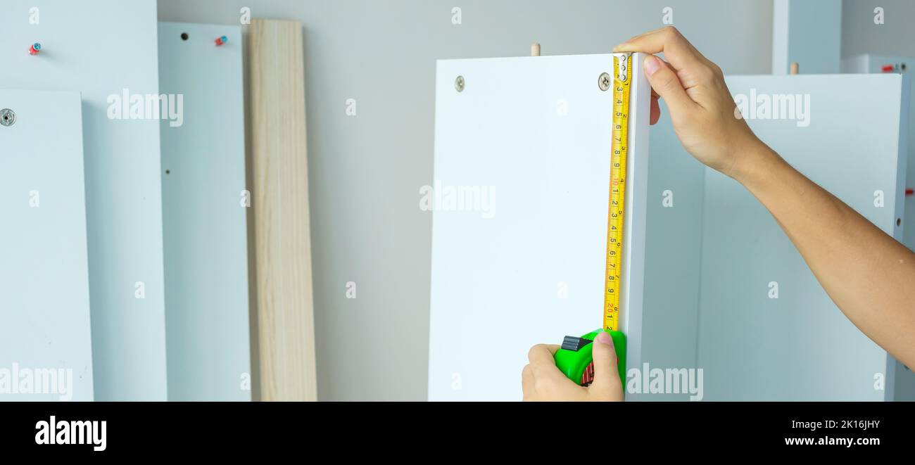 Man hand using tape measure for measuring furniture at home. DIY ...
