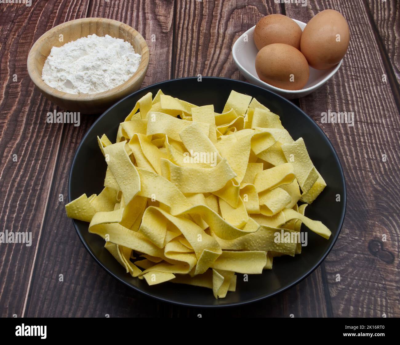 Traditional uncooked Italian Pappardelle on wooden table Stock Photo ...
