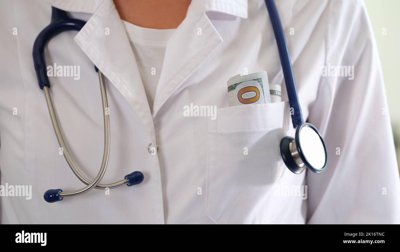 Money dollars in doctor pocket in clinic Stock Photo - Alamy