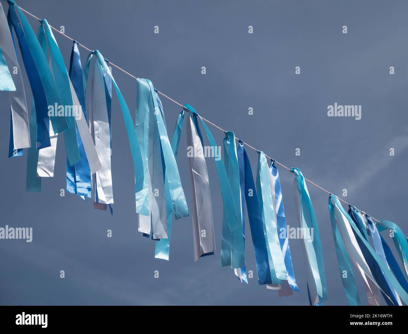 Horizontal photo of a rope with blue colored ribbons from dark to light ...