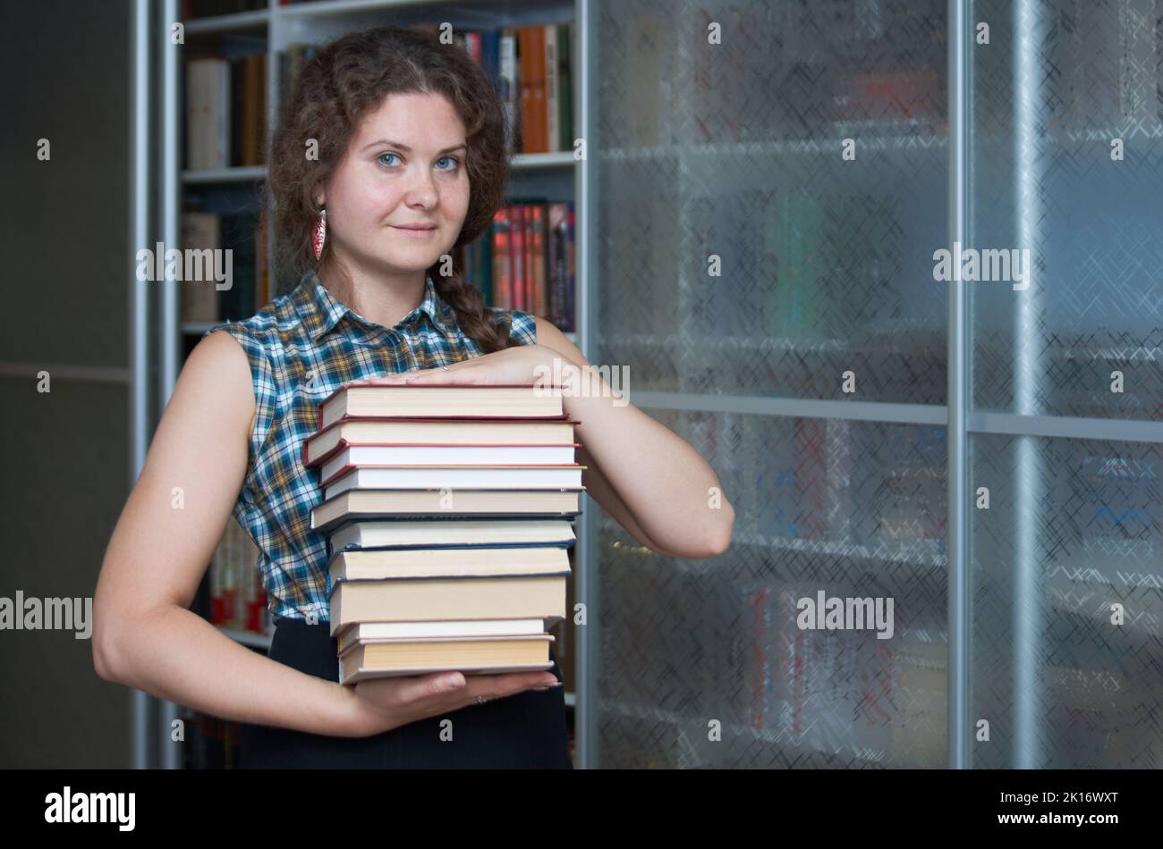 Woman carrying stack of books on the background of a bookcase Stock ...