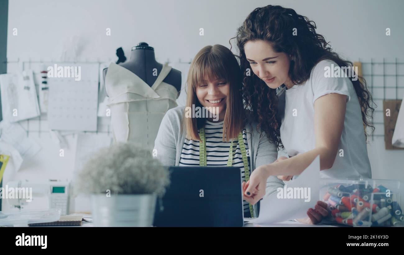 Cheerful creative clothing designers are watching laptop screen, having ...