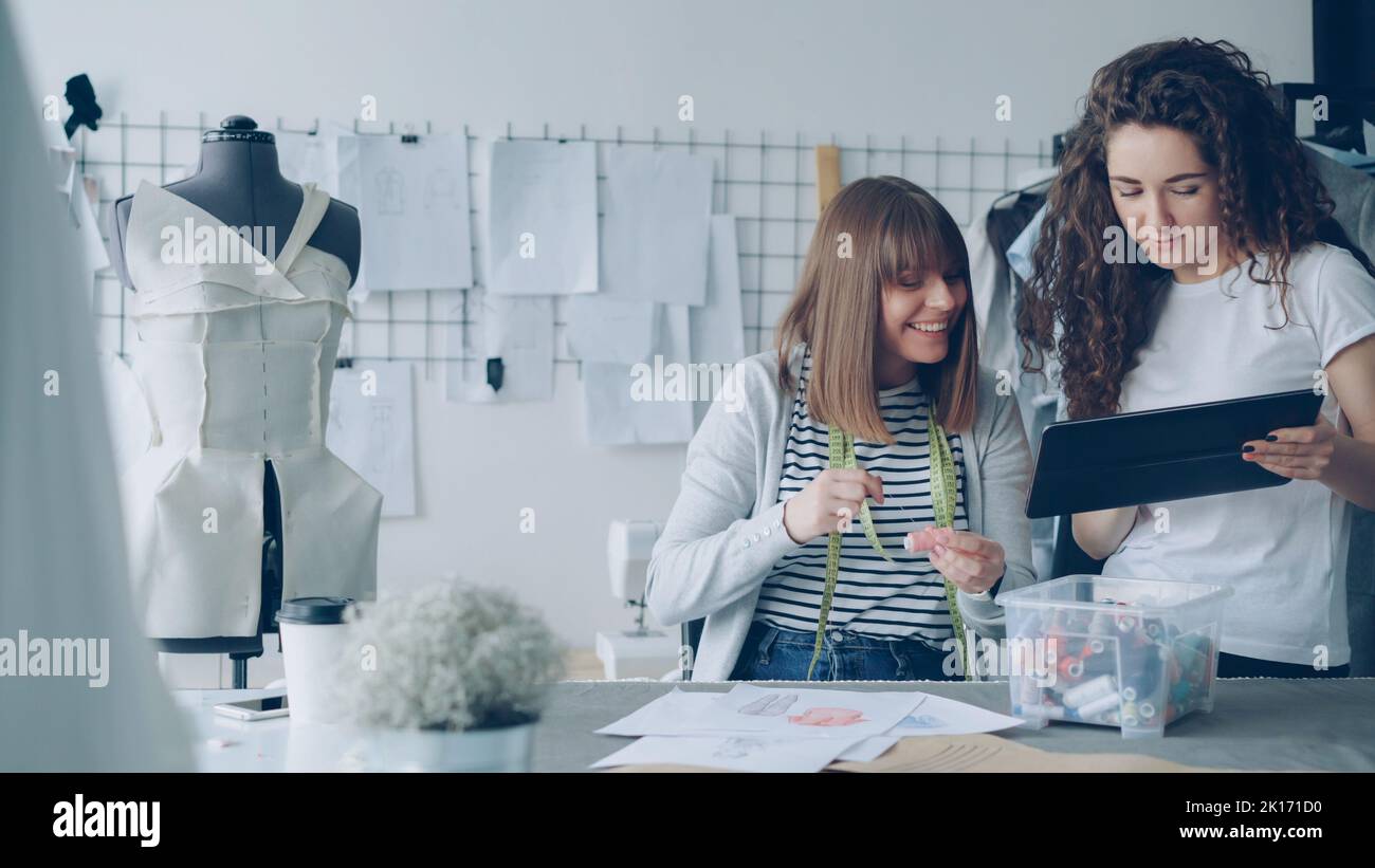 Young clothing design entrepreneurs are watching tablet and choosing ...