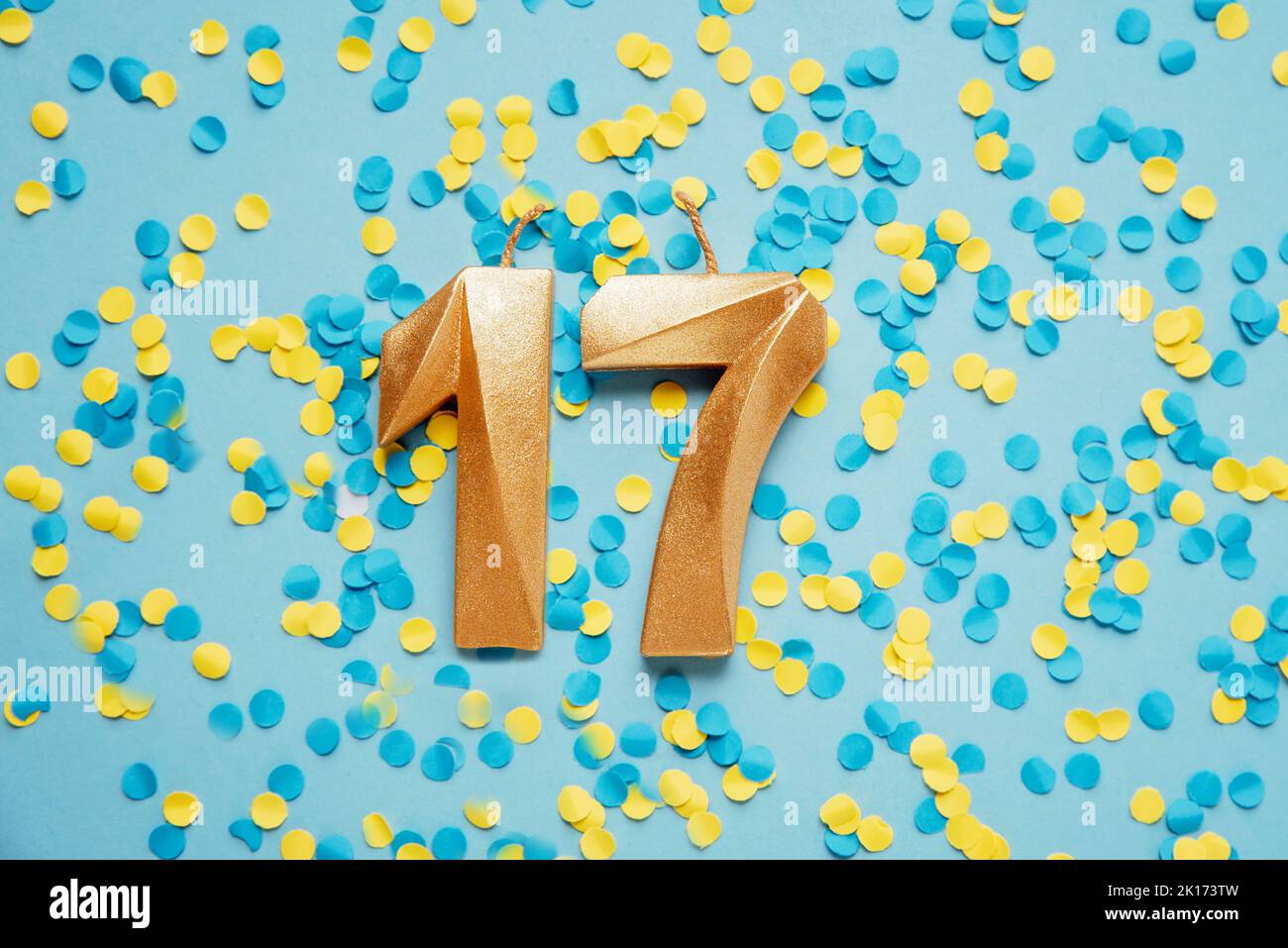 Number 17 seventeen golden celebration birthday candle on yellow and ...