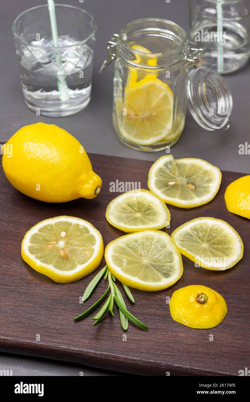 Sliced lemon and whole lemon on board. Water in glass. Lemon slices in ...