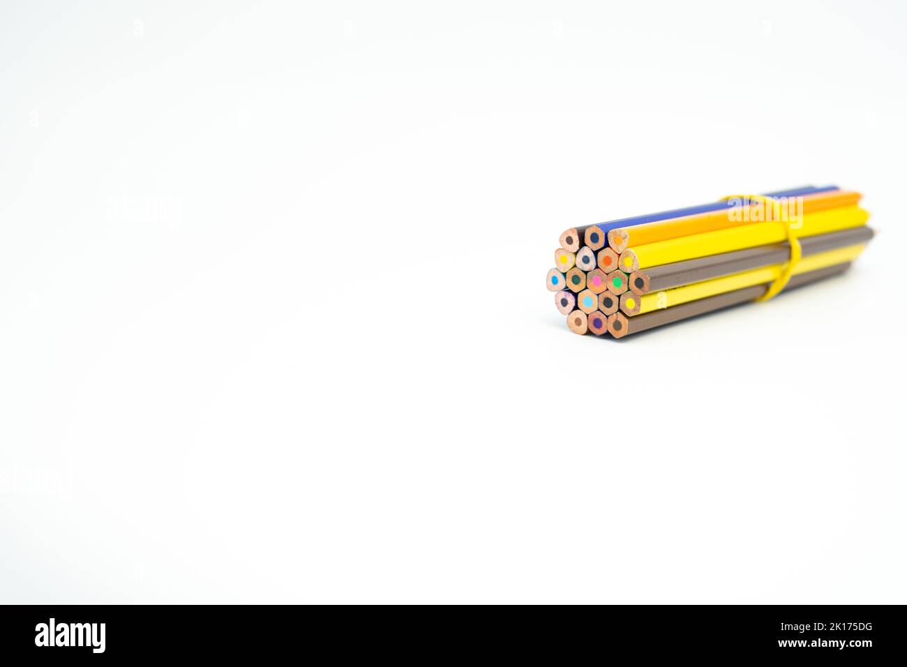 Wooden colored pencils gathered in a bundle with a rubber band on a ...