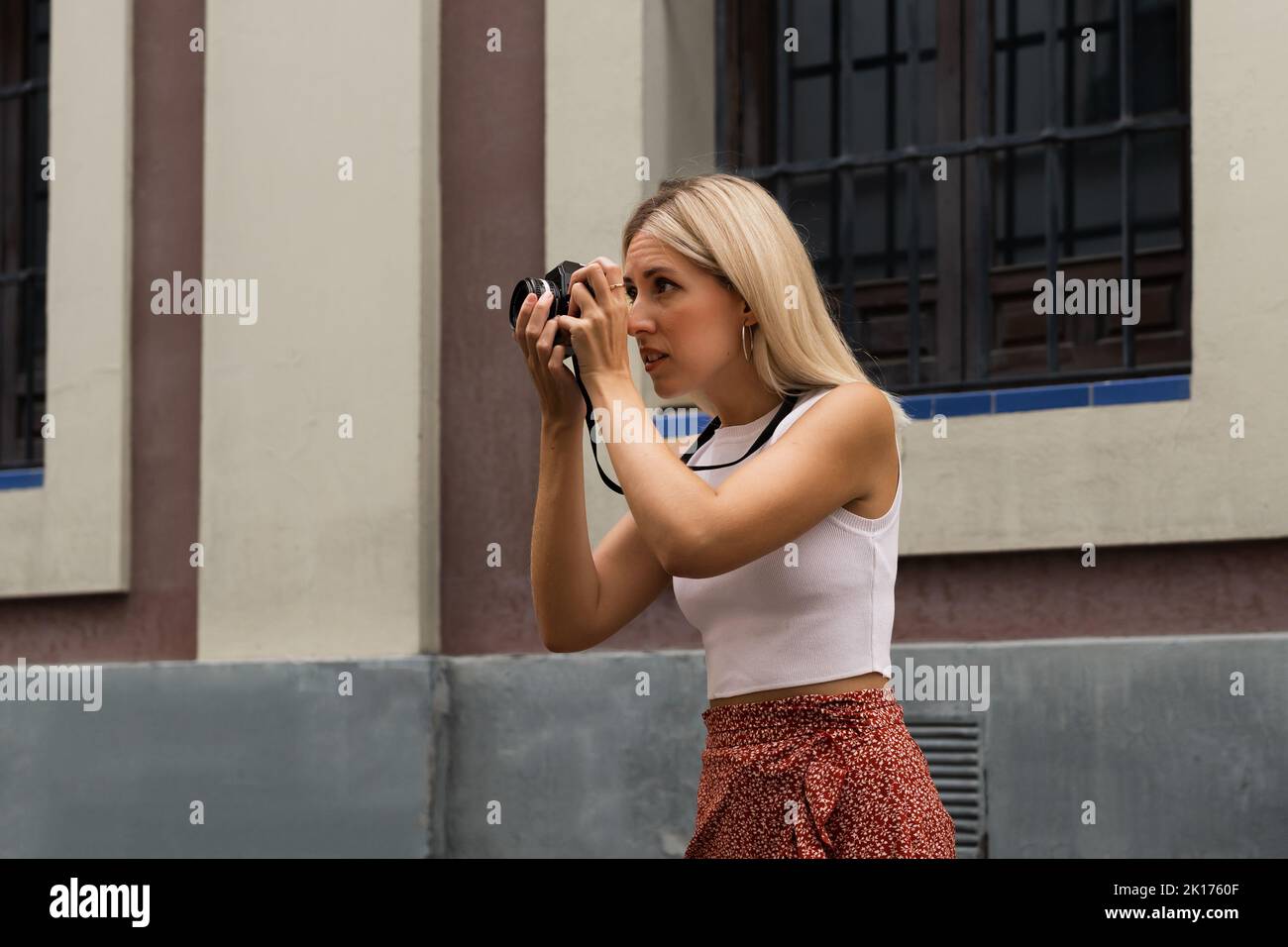 Lone female tourist traveler in Seville, taking a photo with her camera ...