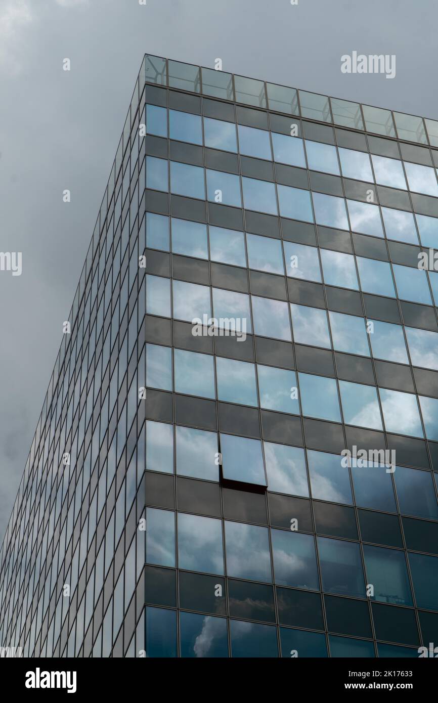 A vertical shot of a tall modern building with glass windows against a ...