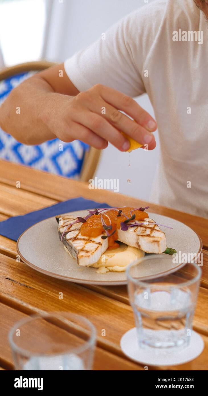 Fish meal with vegetables and potatoes, squeezing the lemon to add a ...