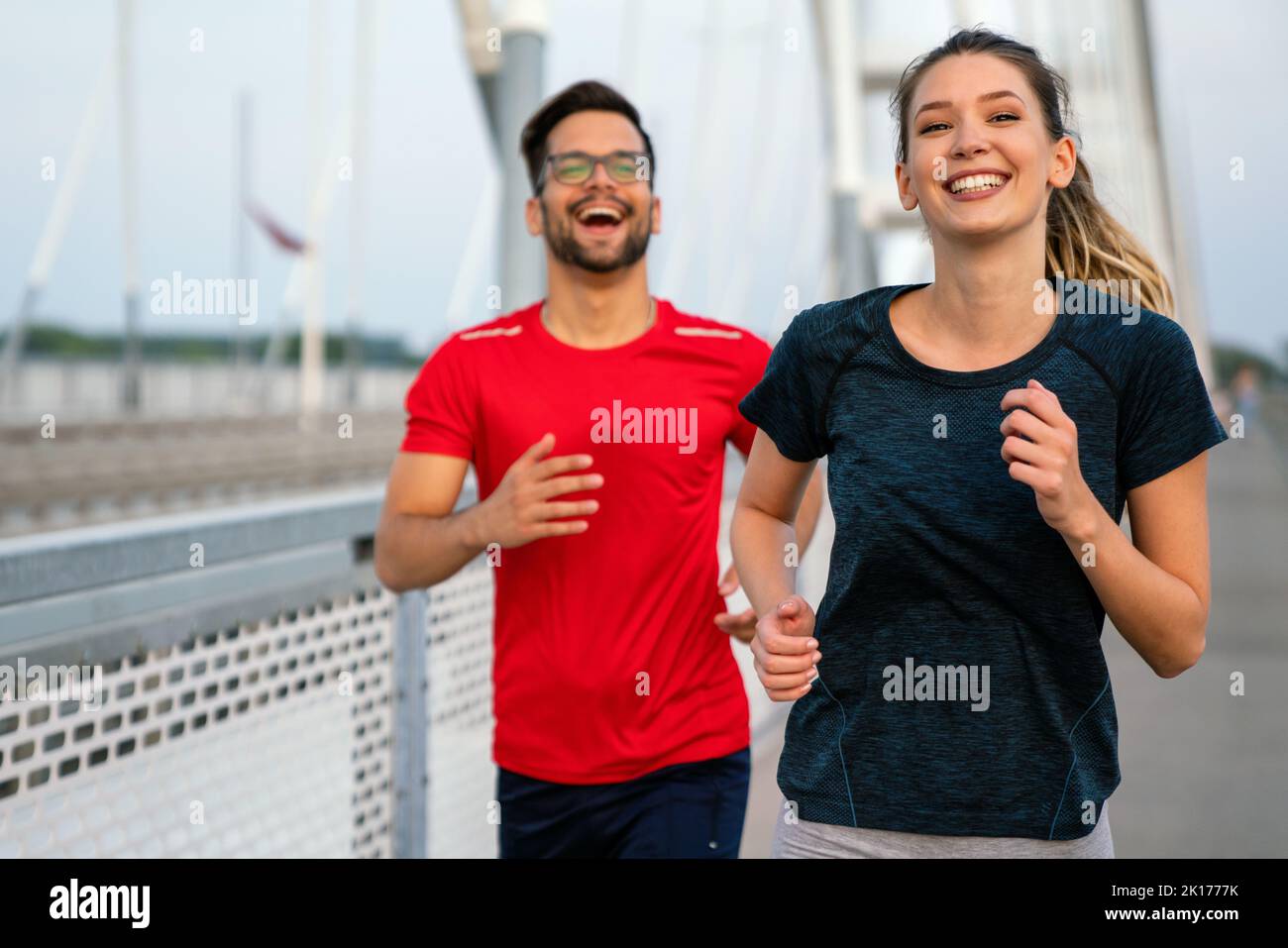 Early morning workout. Happy couple running across the bridge. Sport living healthy lifestyle ...