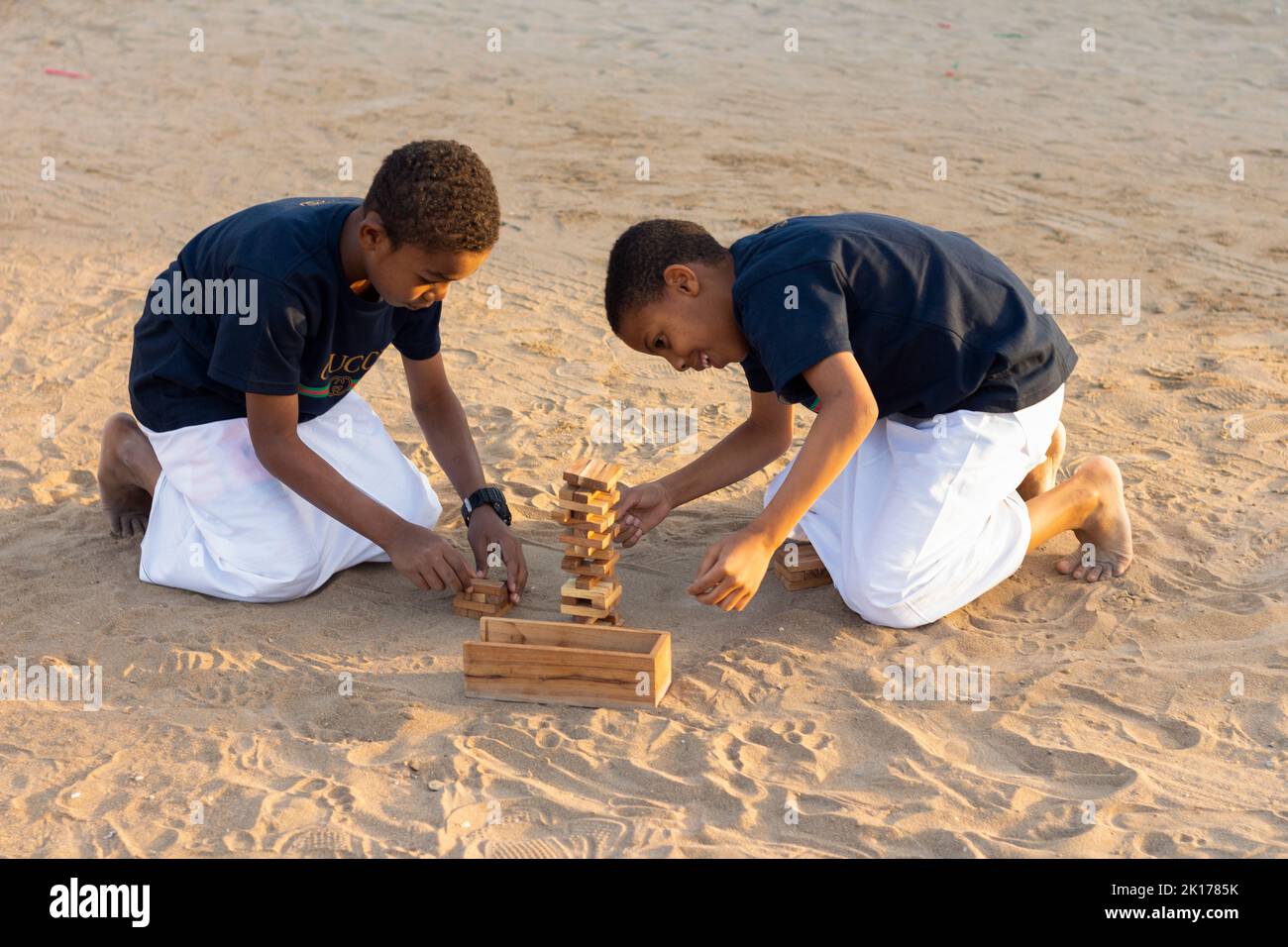 Omani boys playing a traditional game in the sand, representing ...