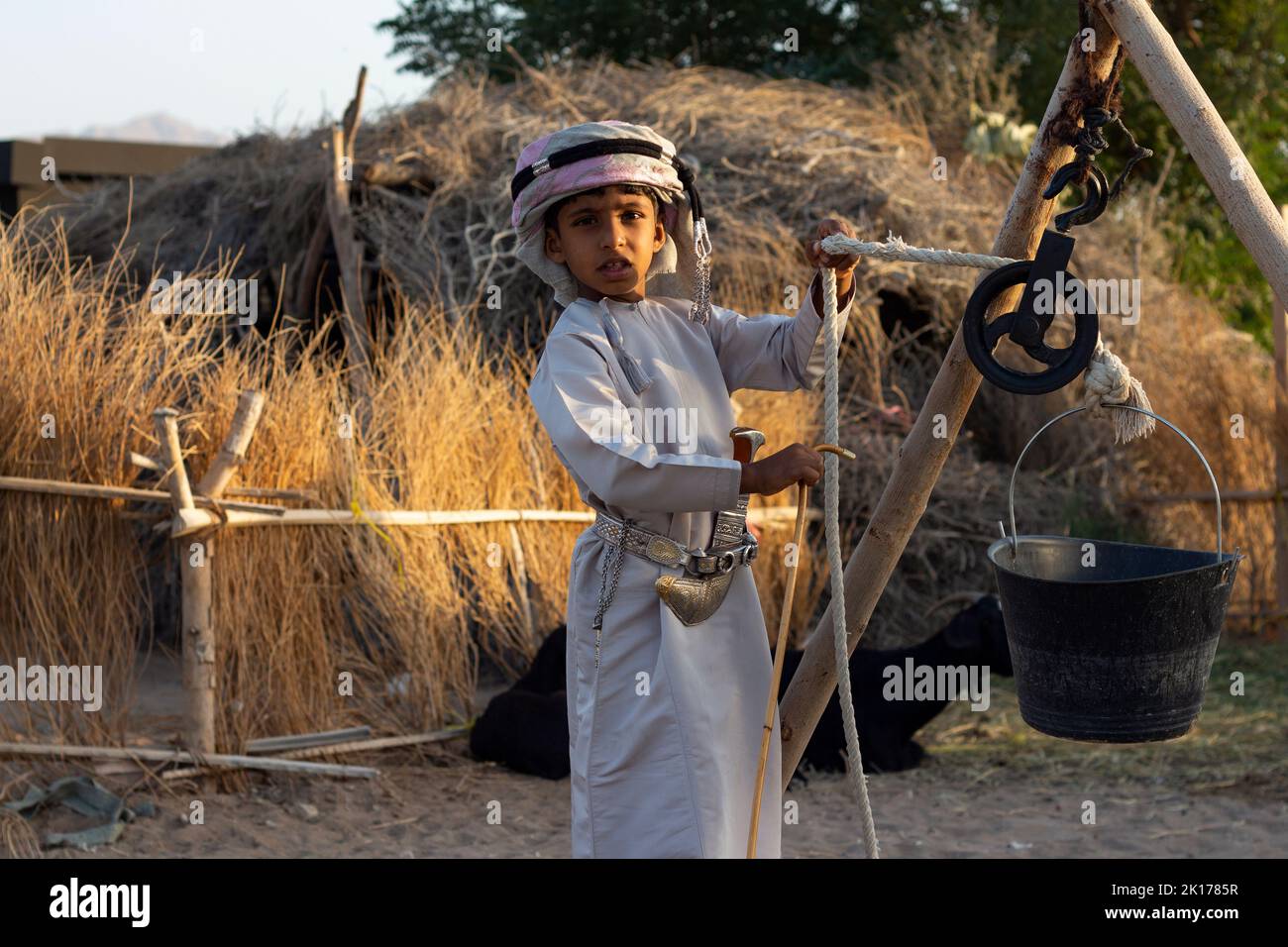 Omani boy drawing water from a traditional well at a heritage village ...