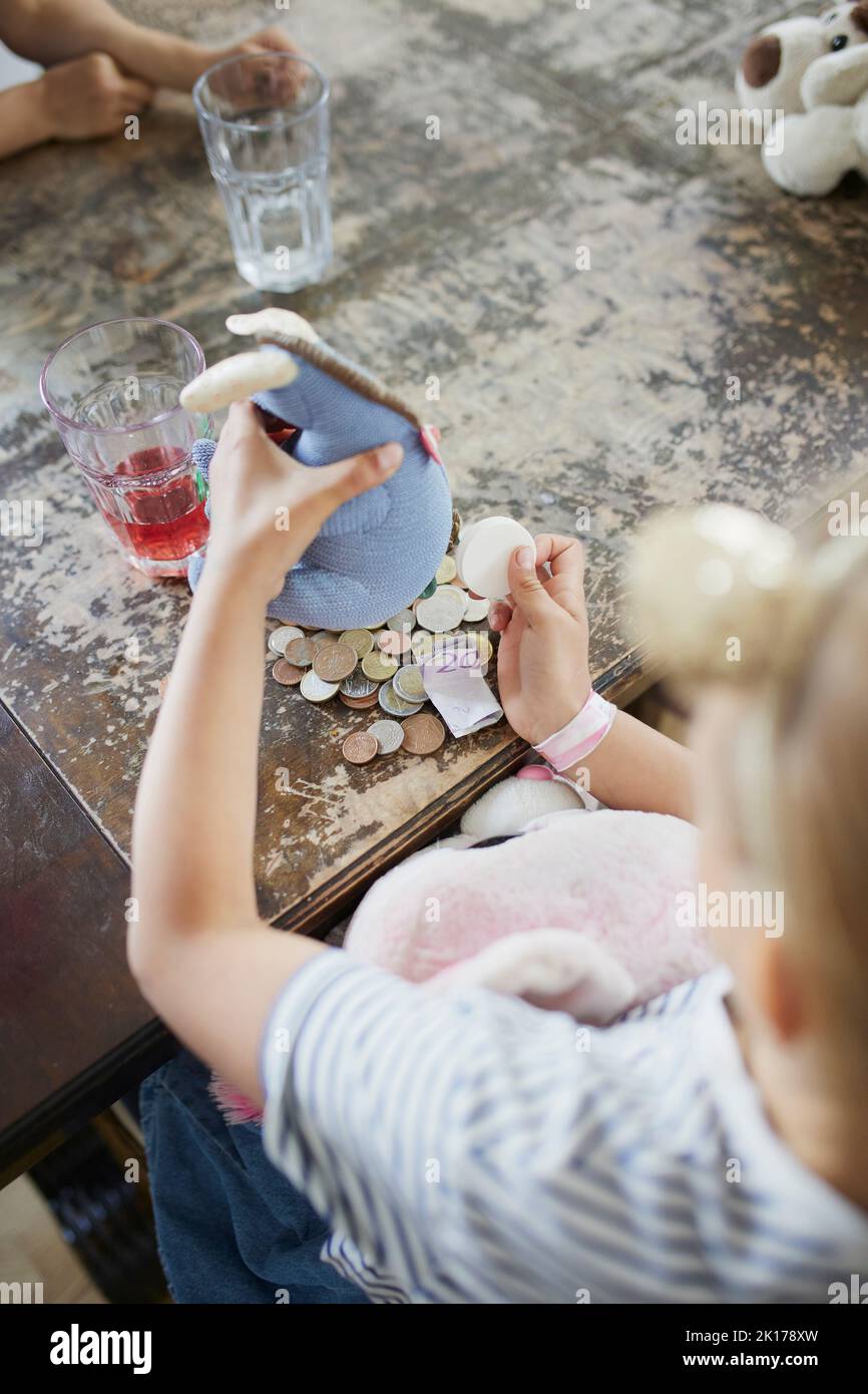 Girl counting savings on table Stock Photo - Alamy