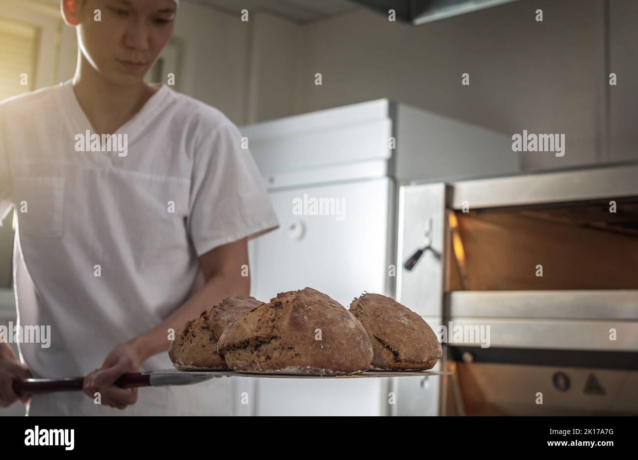The baker is a man in the process of baking bread. Production of bakery ...