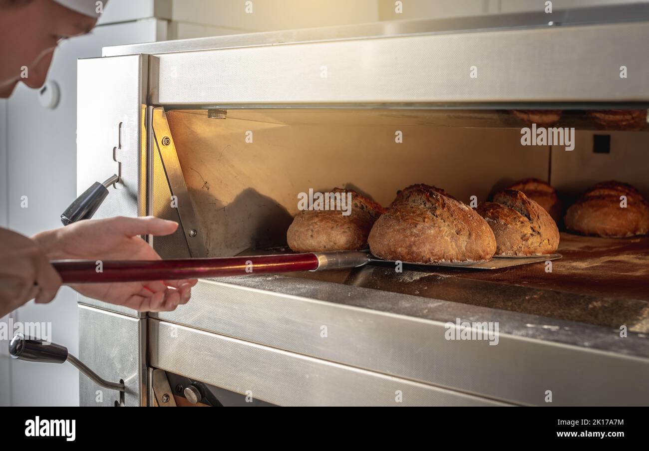 The baker is a man in the process of baking bread. Production of bakery ...