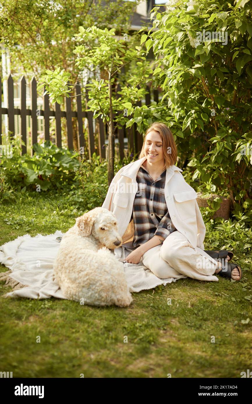 Woman relaxing with dog in garden Stock Photo - Alamy