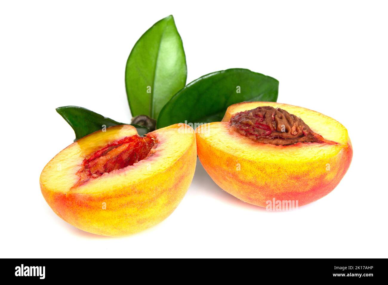 Peach sliced into two halves with leaf on white background isolated ...
