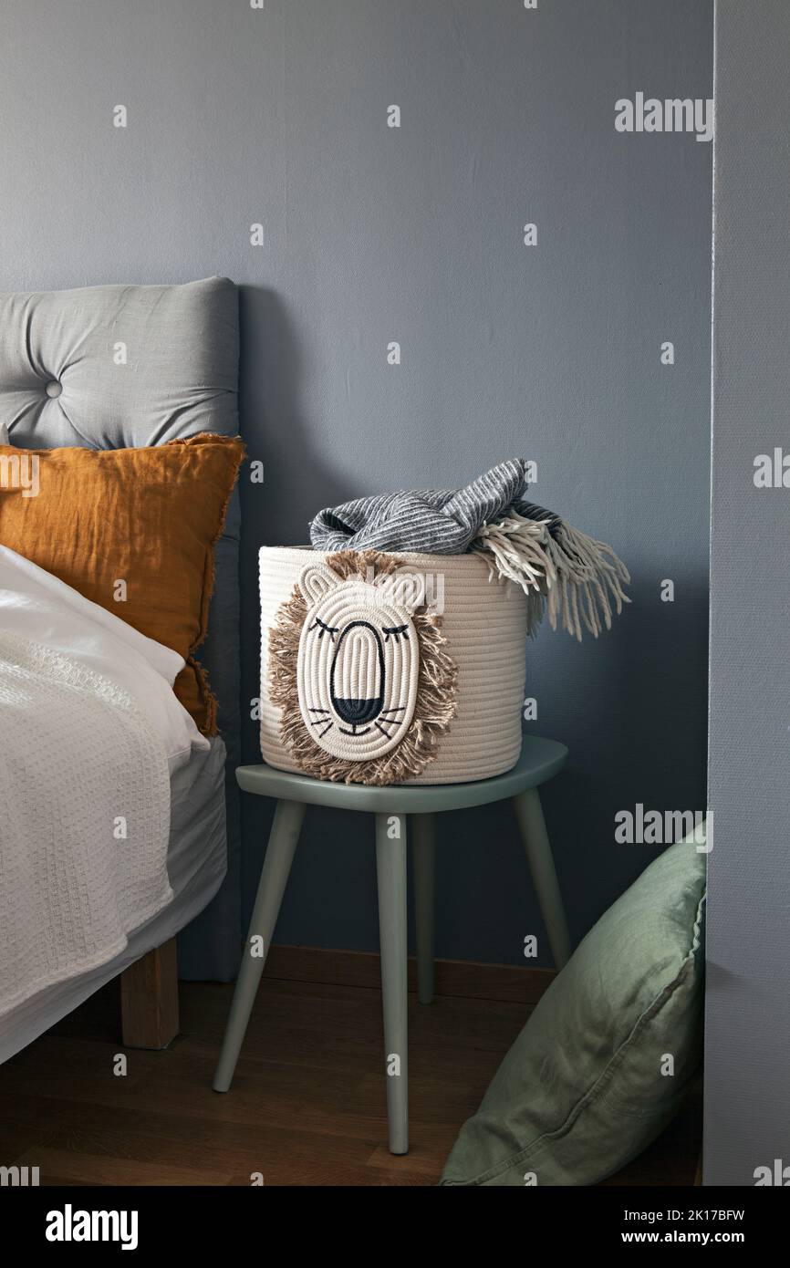 Basket on stool next to bed Stock Photo - Alamy