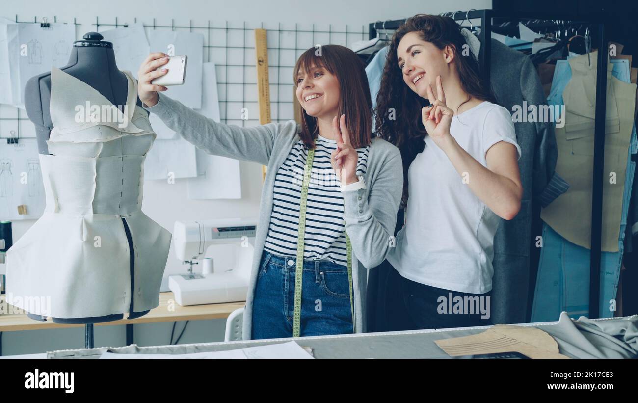 Two cheerful female clothing designers are making funny selfie with ...
