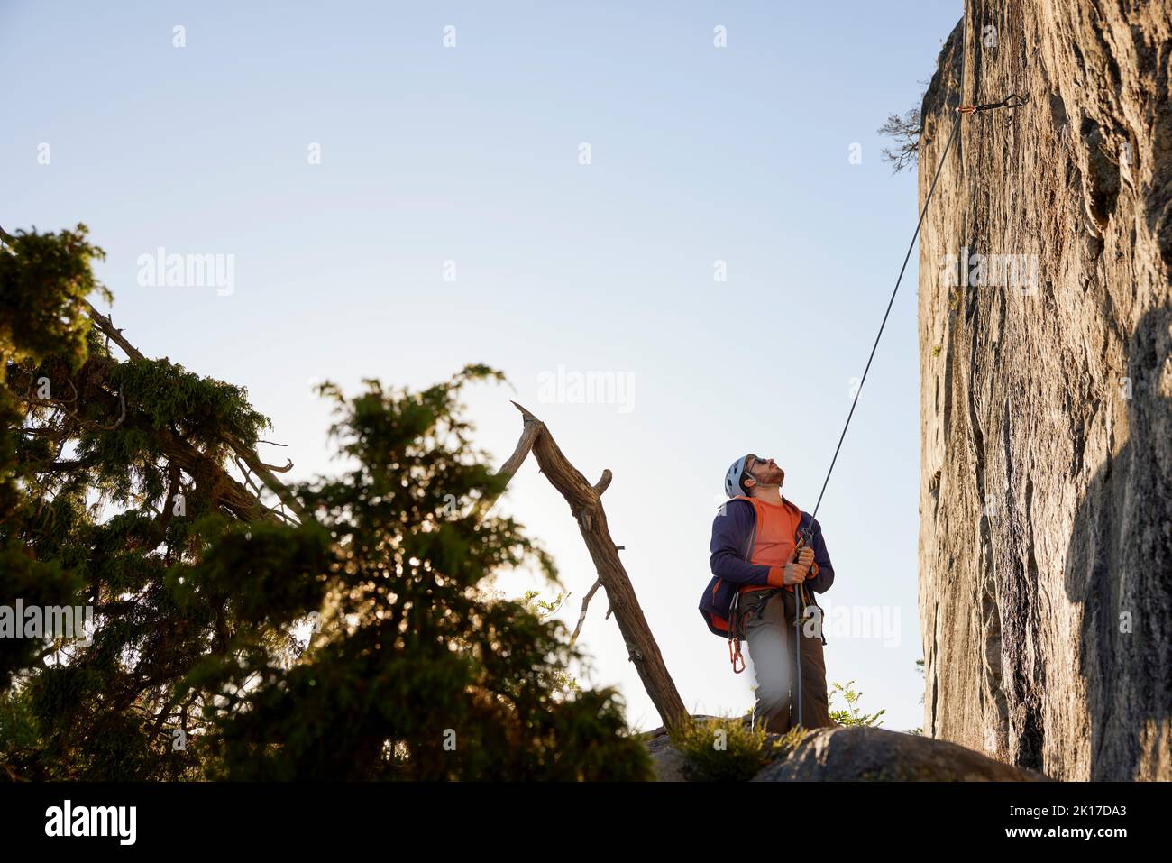 Male rock climber belaying Stock Photo - Alamy