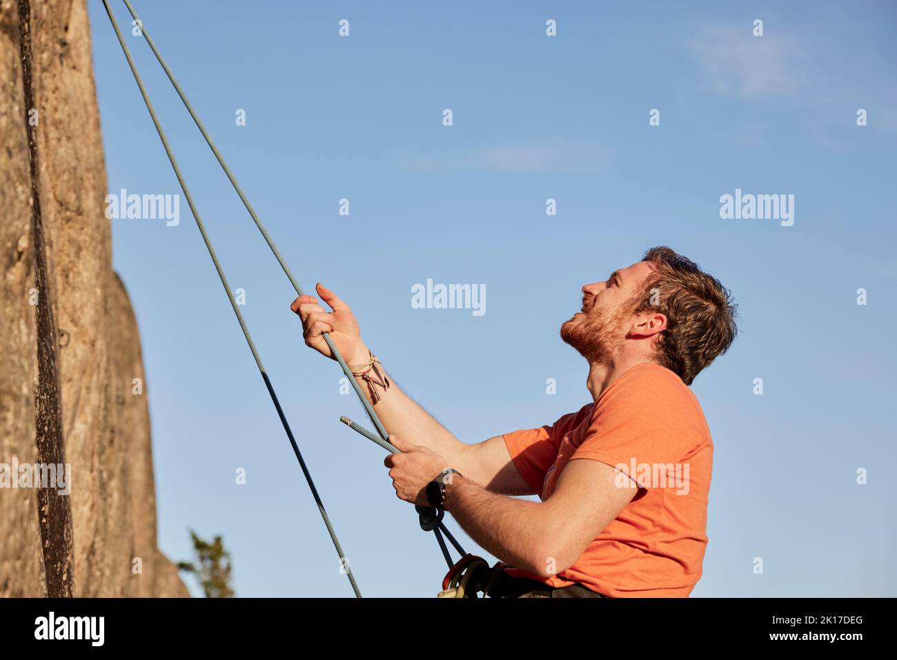 Male rock climber belaying Stock Photo - Alamy