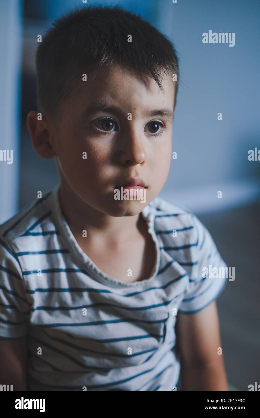 Portrait of a caucasian kid with curious fac sitting on sofa looking ...