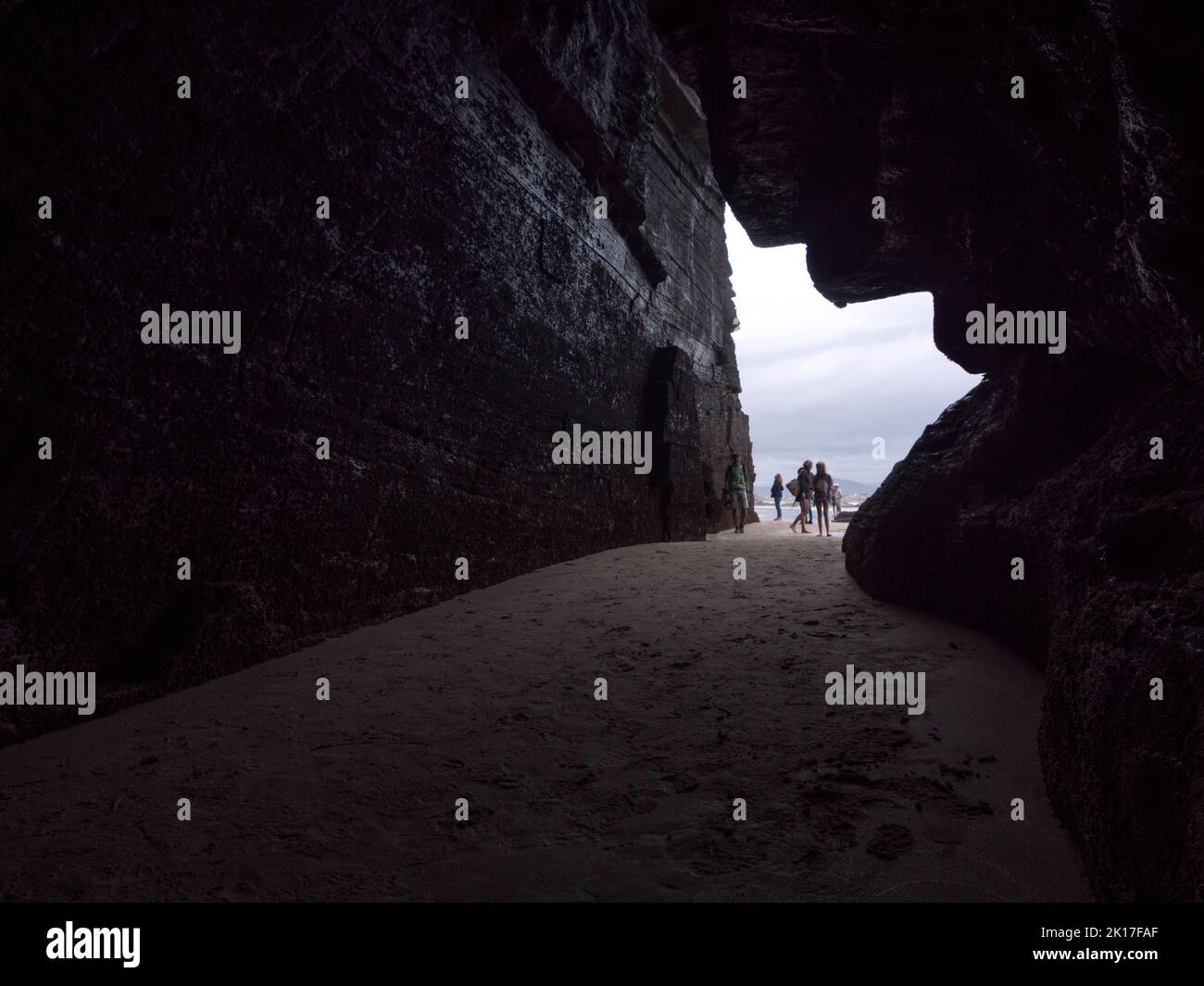 Horizontal view of tourists entering a beach cave in low tide Stock ...
