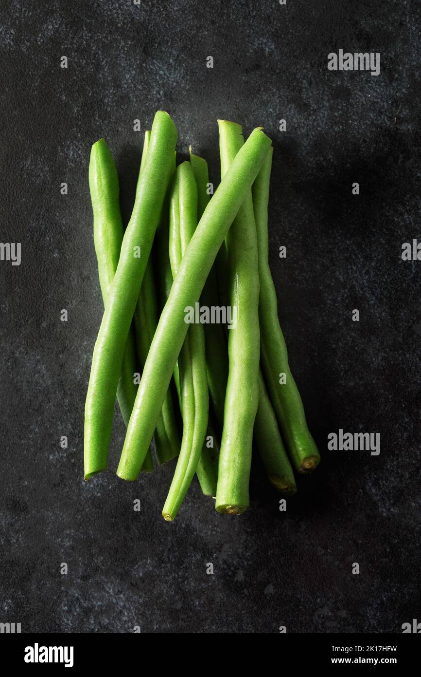 Bunch of trimmed fine green beans shot from above on dark background ...