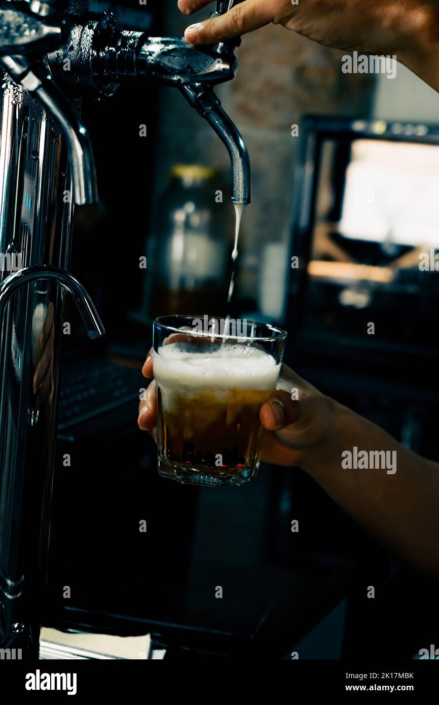 Hand serving beer in glass using tap. Bartender pouring beer while ...