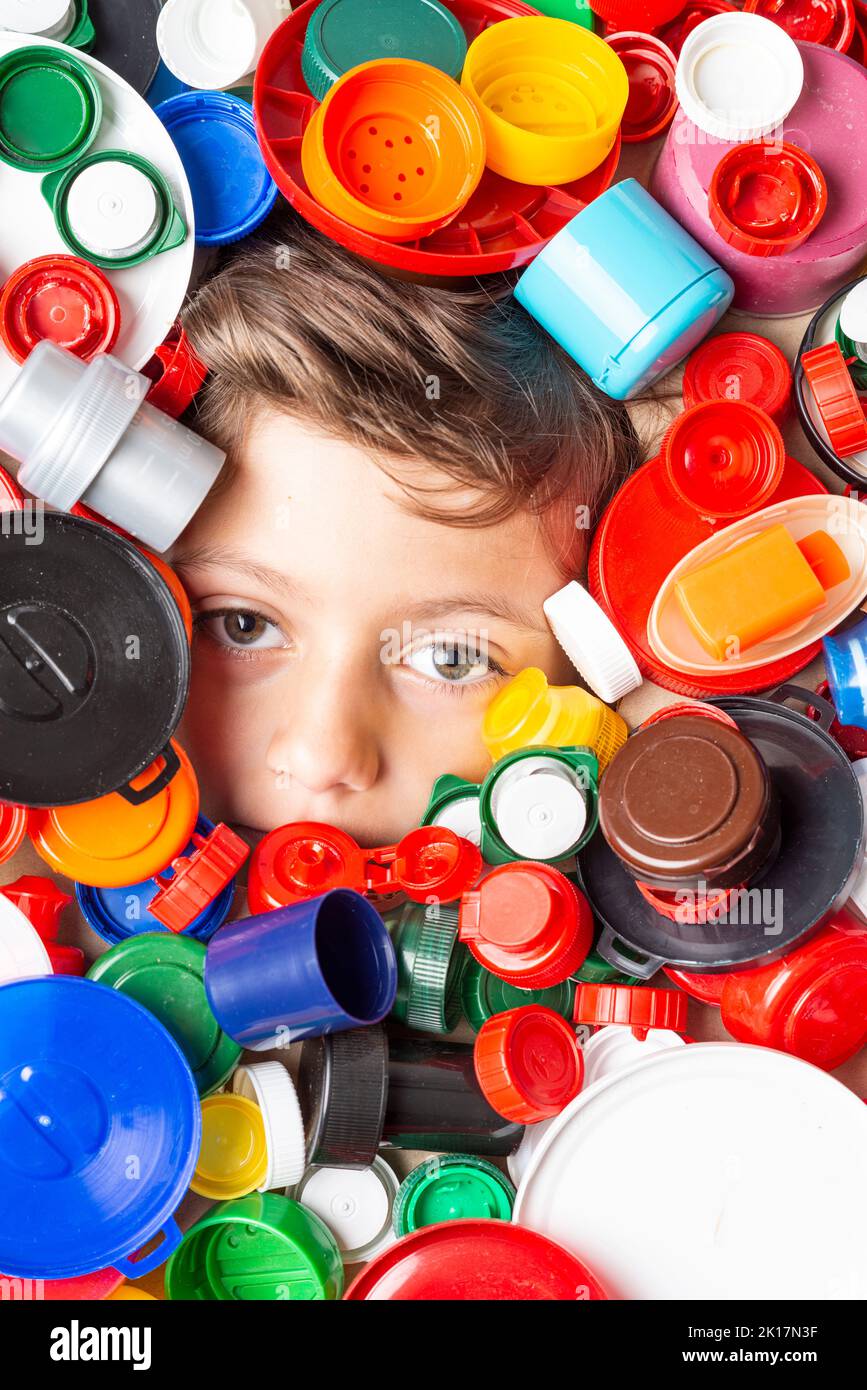 Face of a child surrounded by plastic caps. Conceptual image showing ...