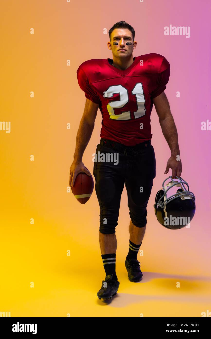 Caucasian male american football player holding helmet and ball with ...