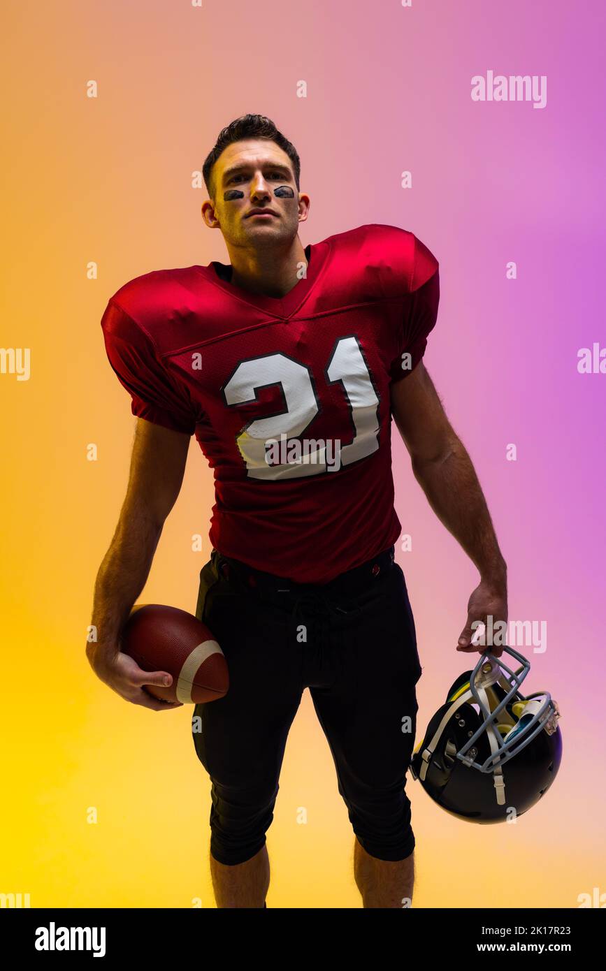 Caucasian male american football player holding helmet and ball with ...
