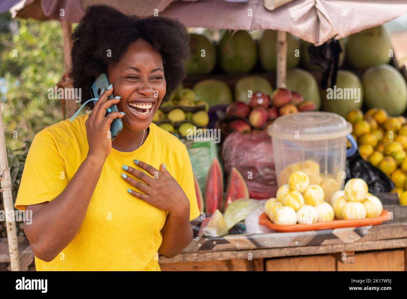 african lady in a market making a phone call excitedly Stock Photo - Alamy