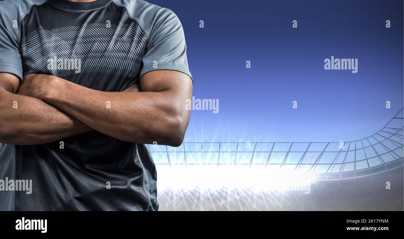Composition of male rugby player with arms crossed over sports stadium ...