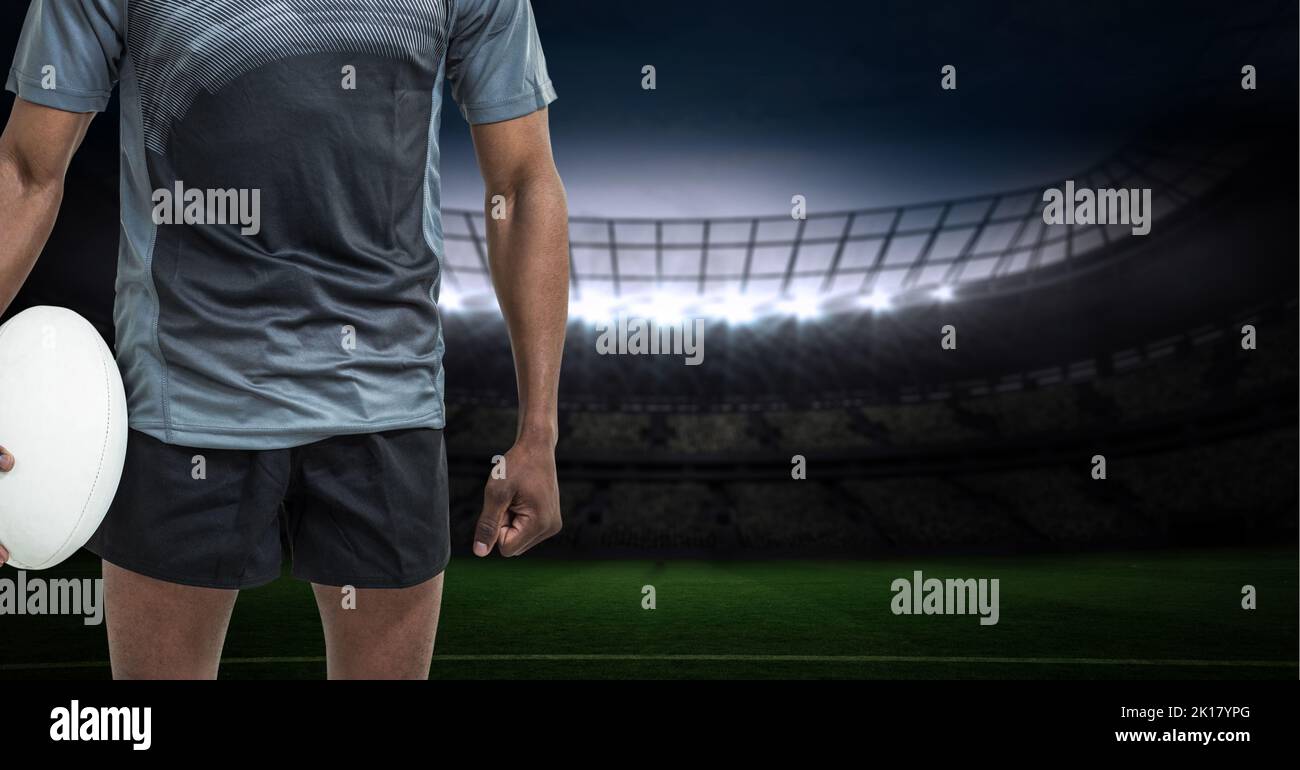 Composition of male rugby player holding rugby ball over sports stadium ...