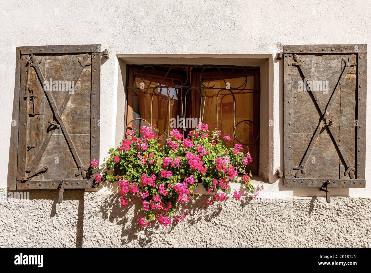 Ancient window with wrought iron security bars, metal shutters and red ...