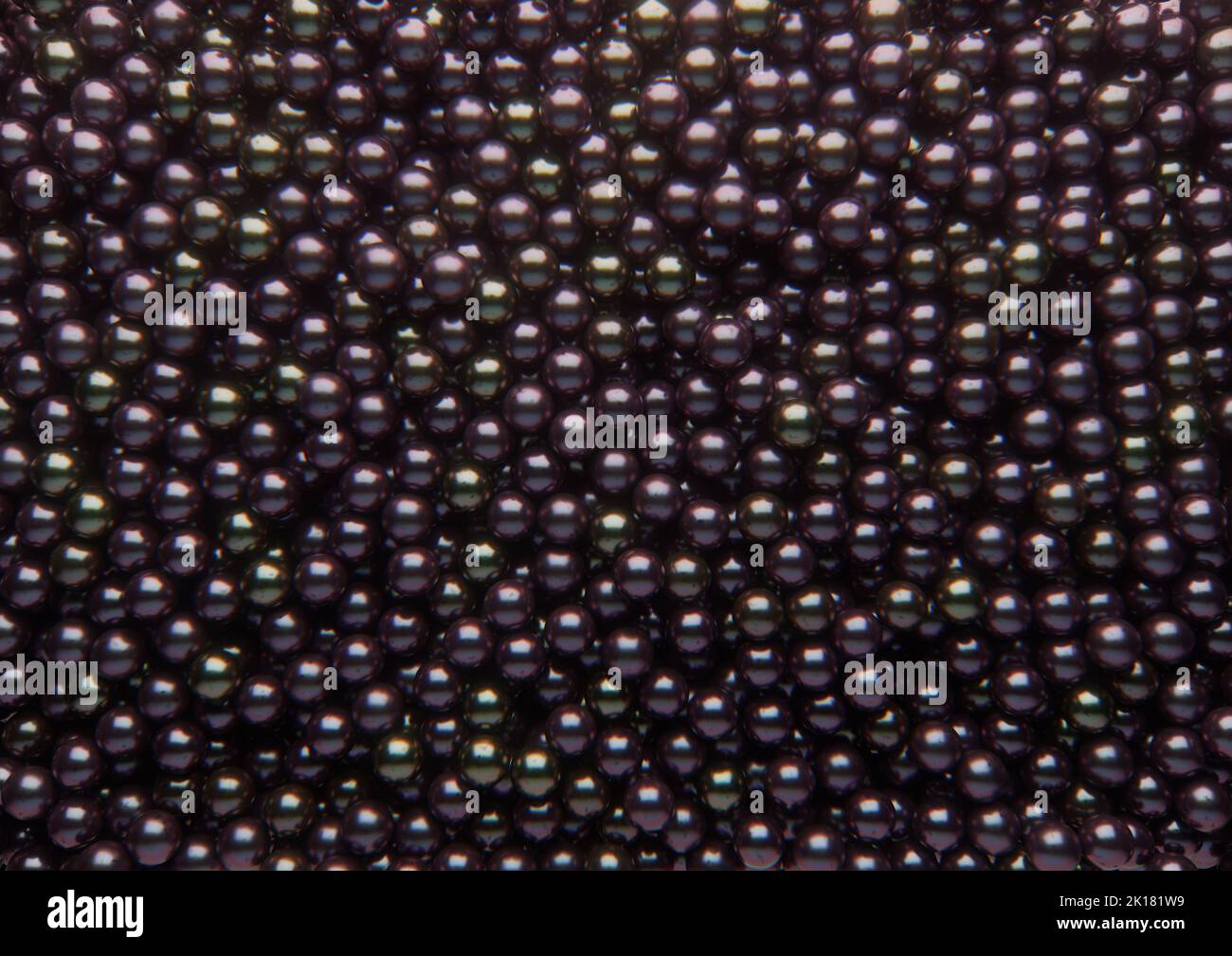 An array of black shiny pearls spread out to form an solid background ...