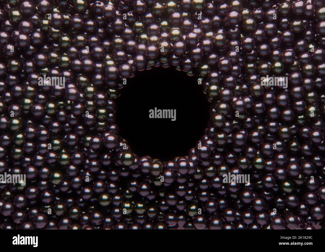 A circular void surrounded by an array of black shiny pearls spread out ...