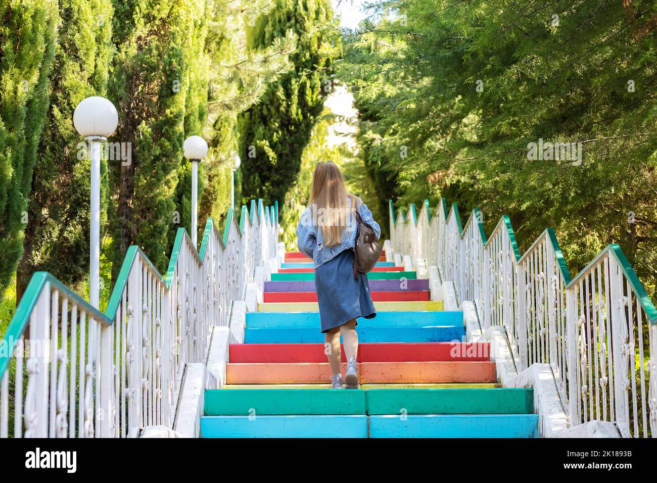 A woman climbs up colored, multi-colored stairs. Concrete colored steps ...