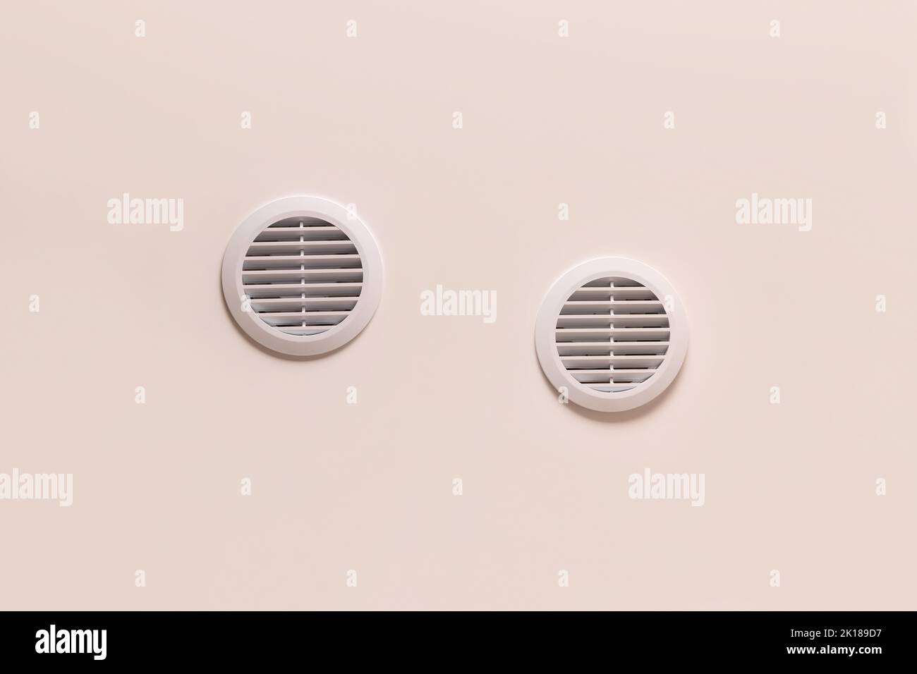 Round air vents with white plastic grate on beige ceiling Stock Photo ...