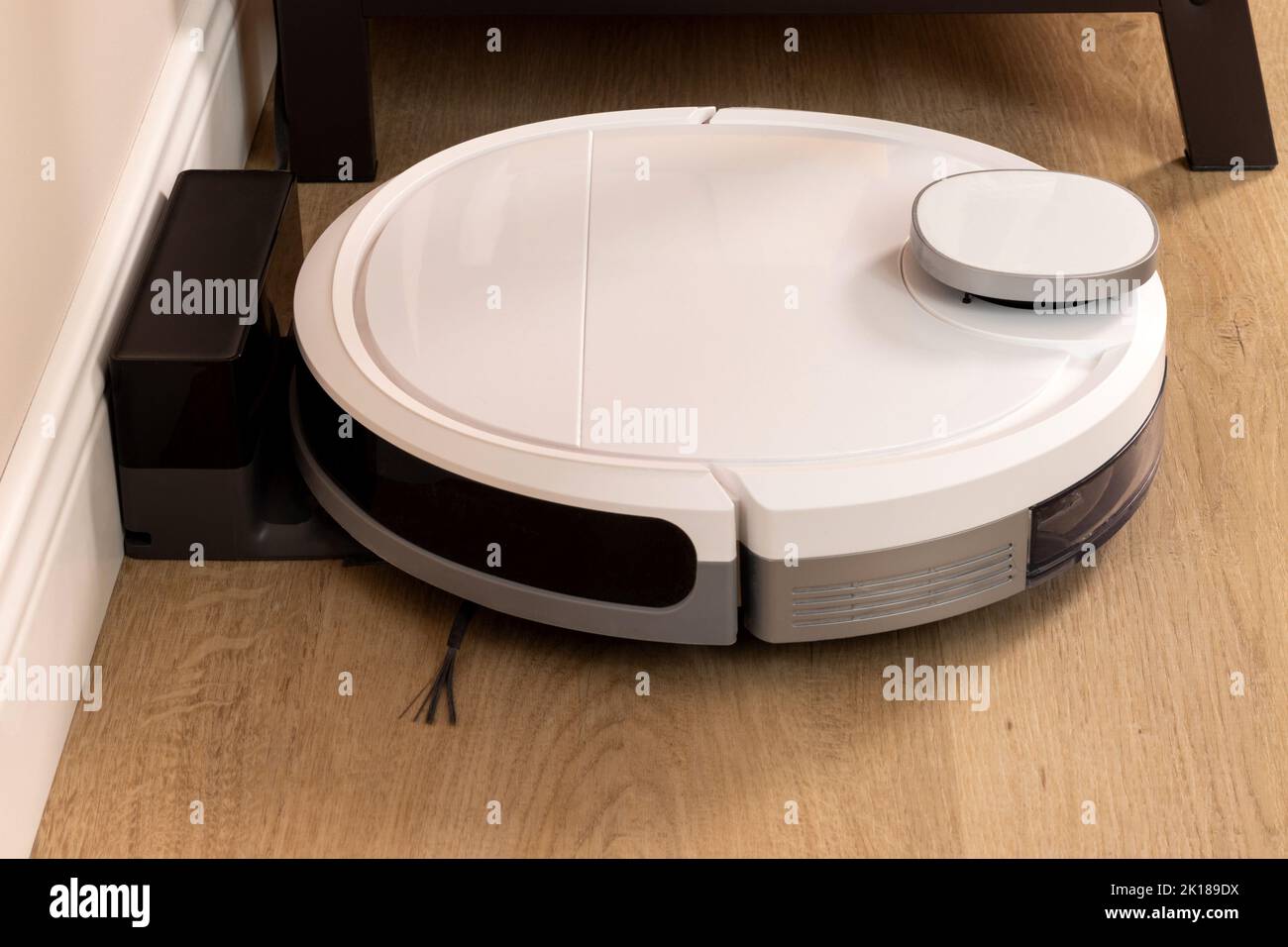 Modern white robot vacuum cleaner based on wooden floor Stock Photo - Alamy