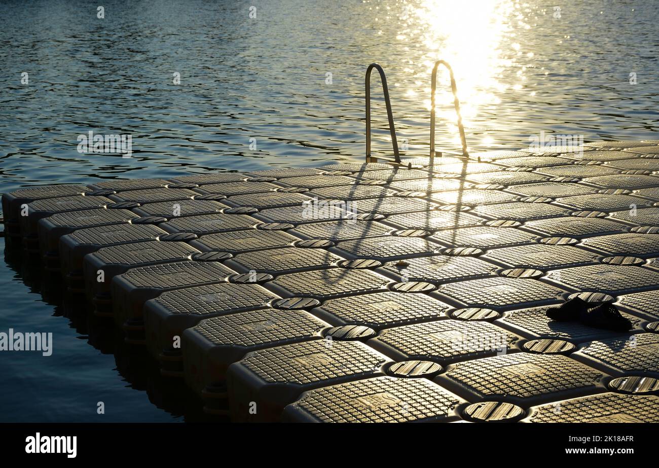floating pier in the sunset on sparkling water, with an abandoned ...