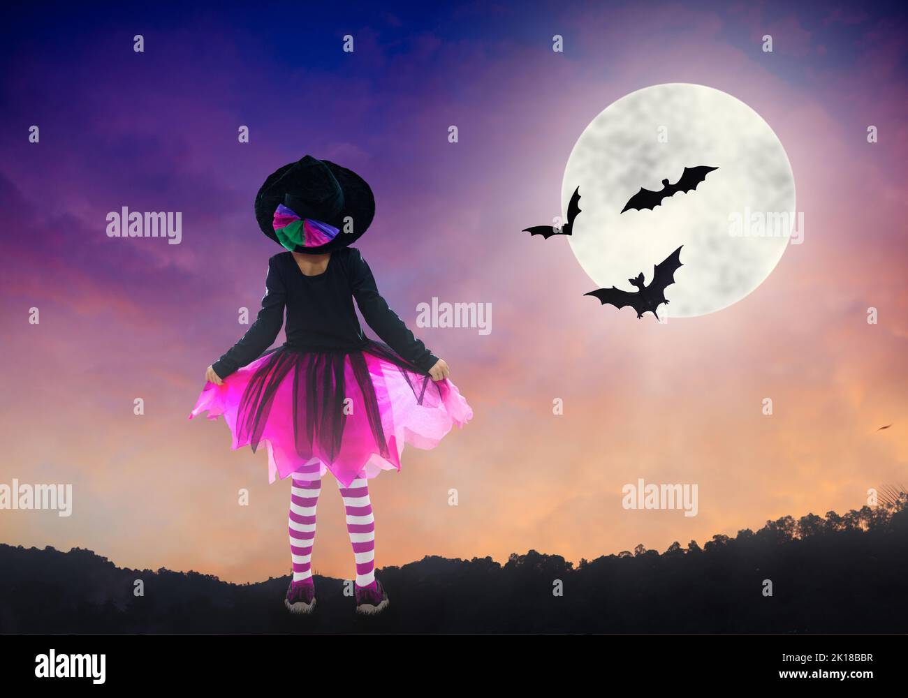 Little witch flying broom on Halloween night. Huge full moon and bats ...