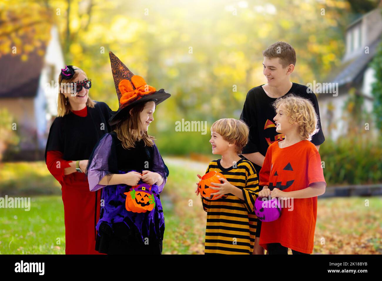 Family trick or treating on Halloween night. Kids in witch and pumpkin ...
