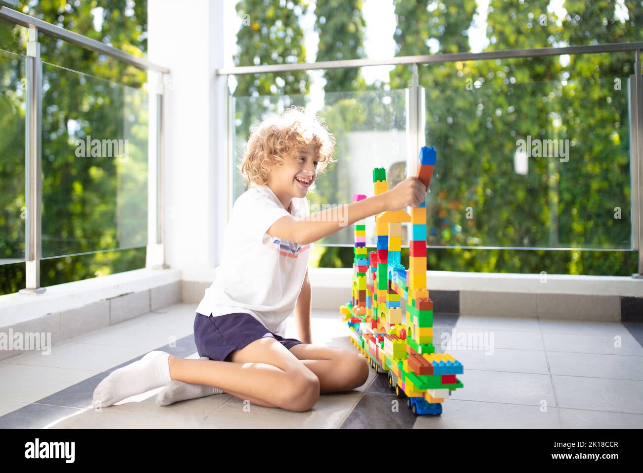 Child playing on home balcony. Outdoor patio of city apartment building ...