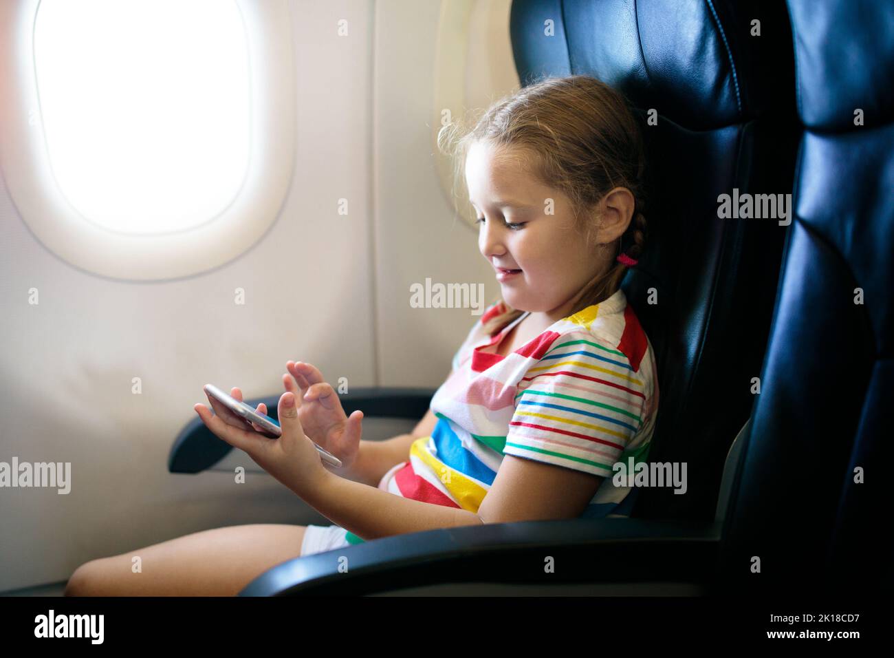 Child in airplane. Kid with mobile phone in air plane in window seat ...
