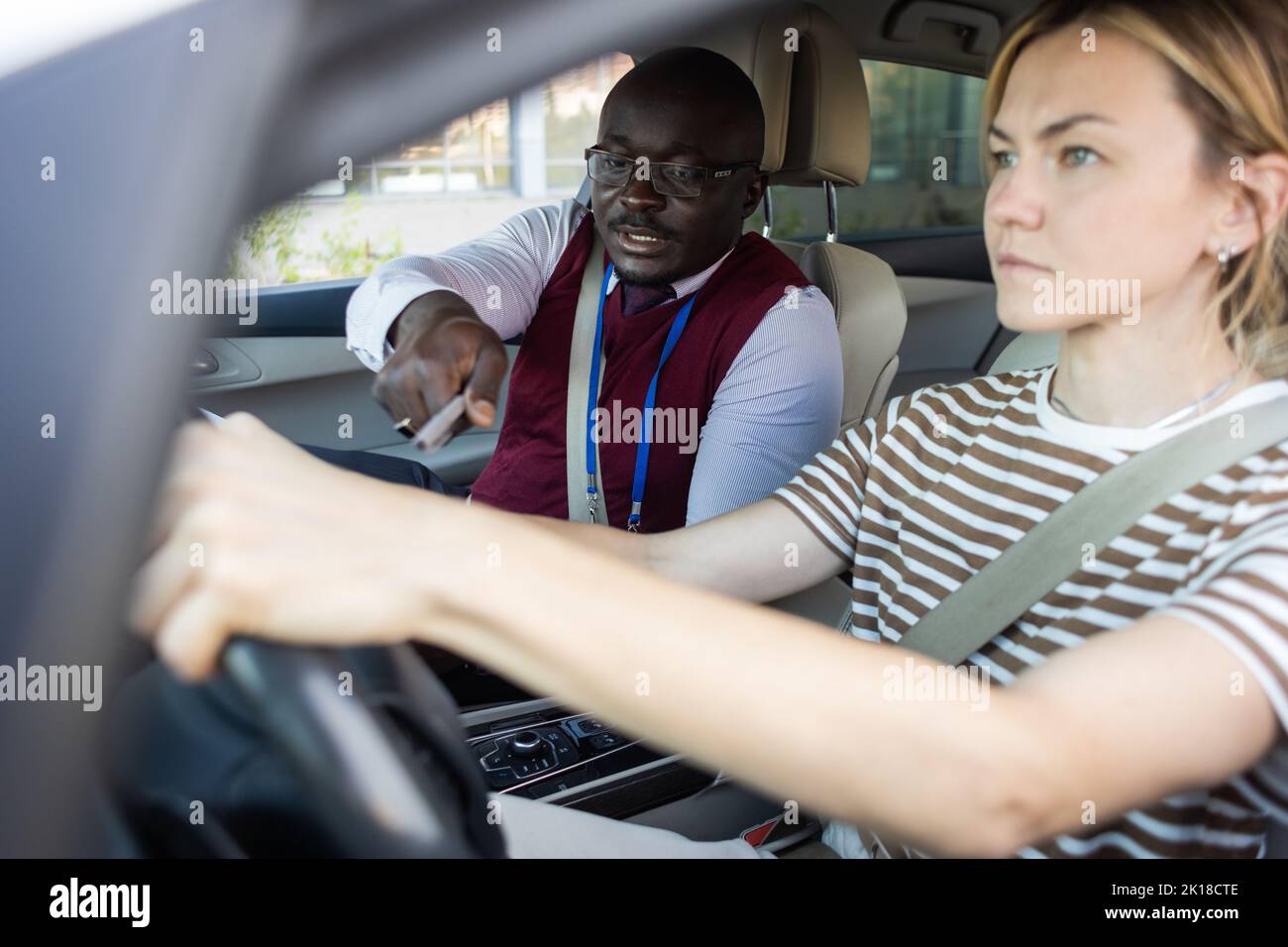 Driving school concept. A car instructor teaches a young woman how to ...